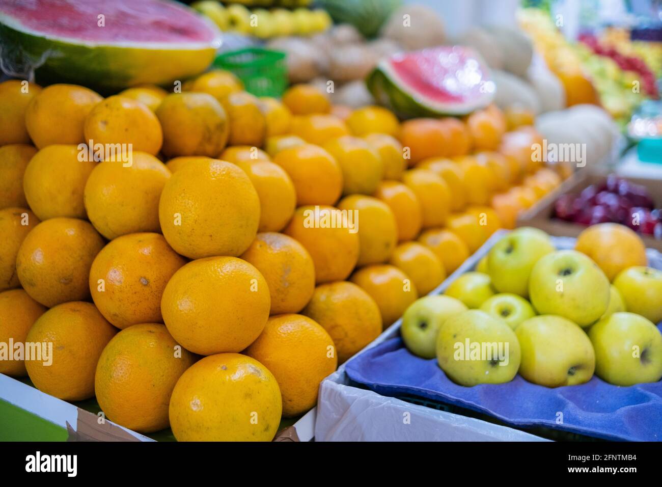 Colorful fruit stand with oranges, sliced watermelon, apples, and more ...