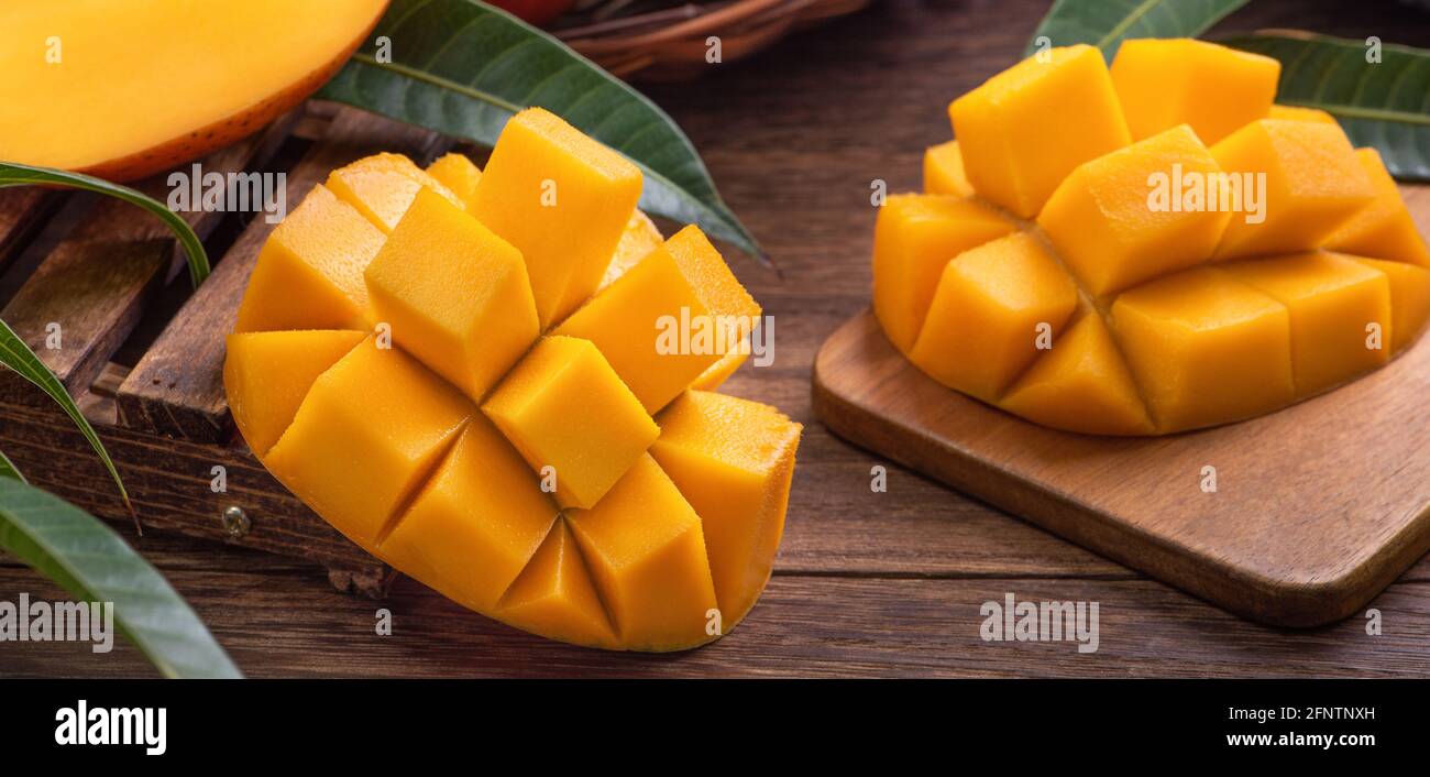 Mango. Close up of fresh ripe mango fruit with leaves over dark wooden ...