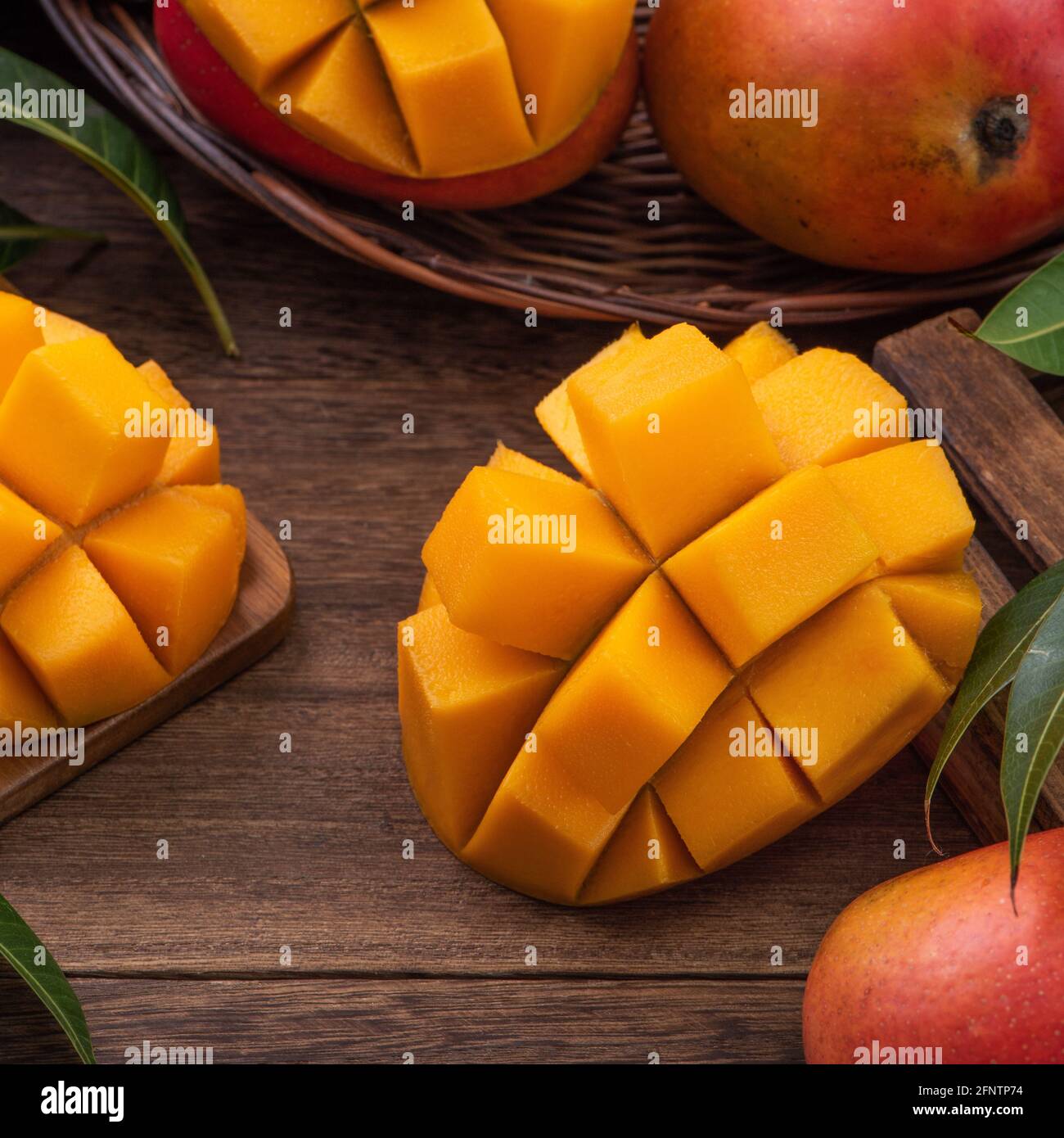 Mango. Close up of fresh ripe mango fruit with leaves over dark wooden ...