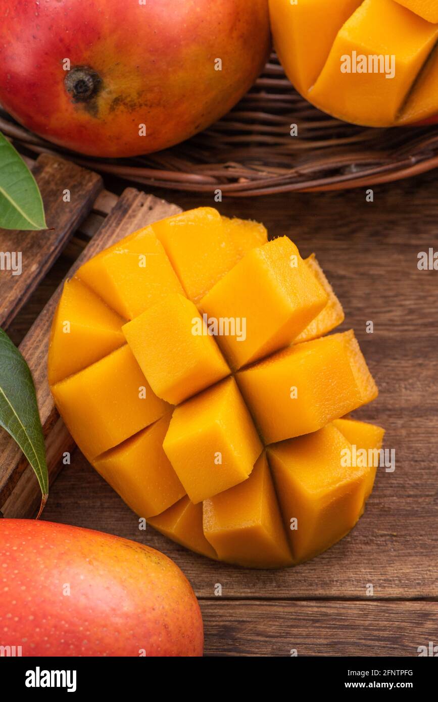 Mango. Close up of fresh ripe mango fruit with leaves over dark wooden ...