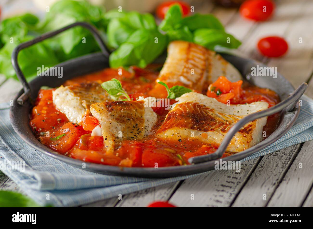 Grilled fish in tomato sauce with basil and herbs Stock Photo - Alamy