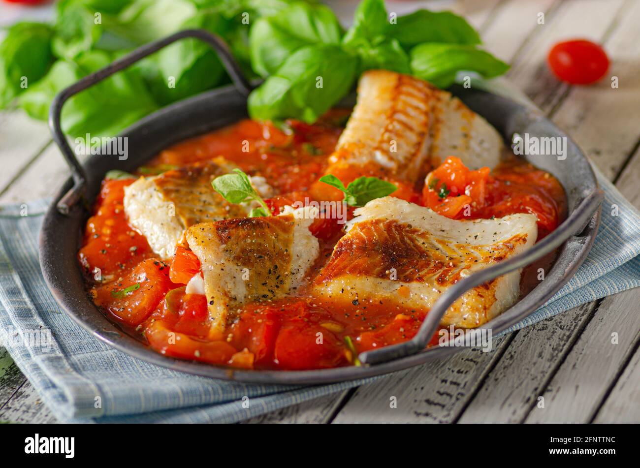 Grilled fish in tomato sauce with basil and herbs Stock Photo - Alamy