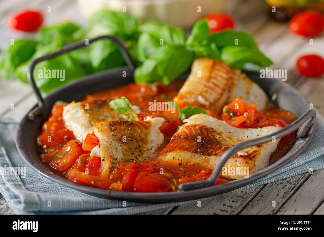 Grilled fish in tomato sauce with basil and herbs Stock Photo - Alamy