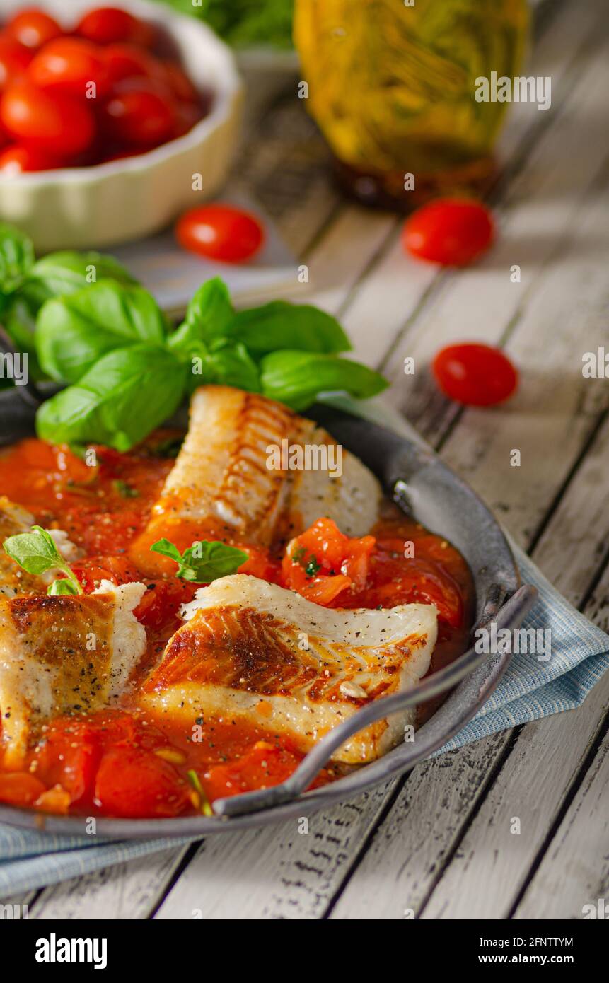 Grilled fish in tomato sauce with basil and herbs Stock Photo - Alamy