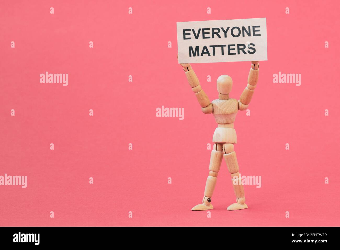 Wooden man holding a card with text "EVERYONE MATTERS" . Equality and ...