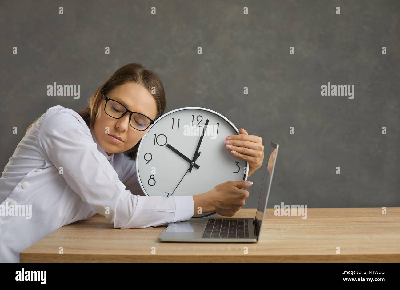 Employee freelancer sleeping at work hugging clock at desk front of ...