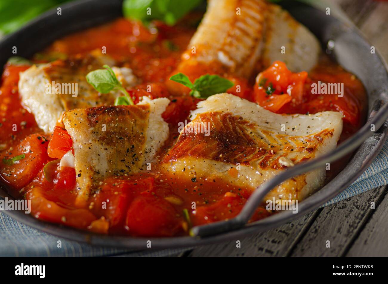 Grilled fish in tomato sauce with basil and herbs Stock Photo - Alamy