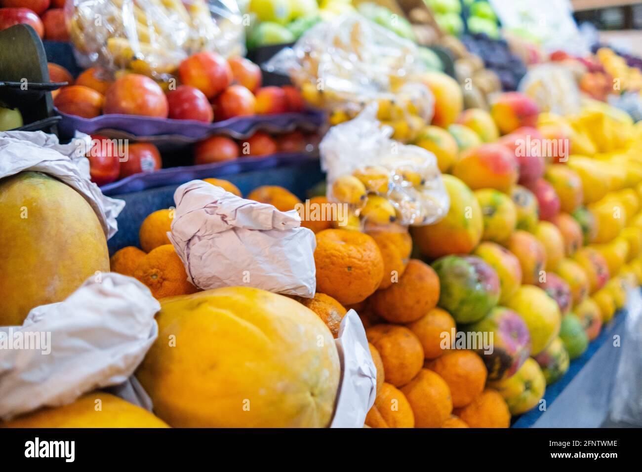 Colorful fruit stand with papayas, tangerines, apples, mangoes and more ...