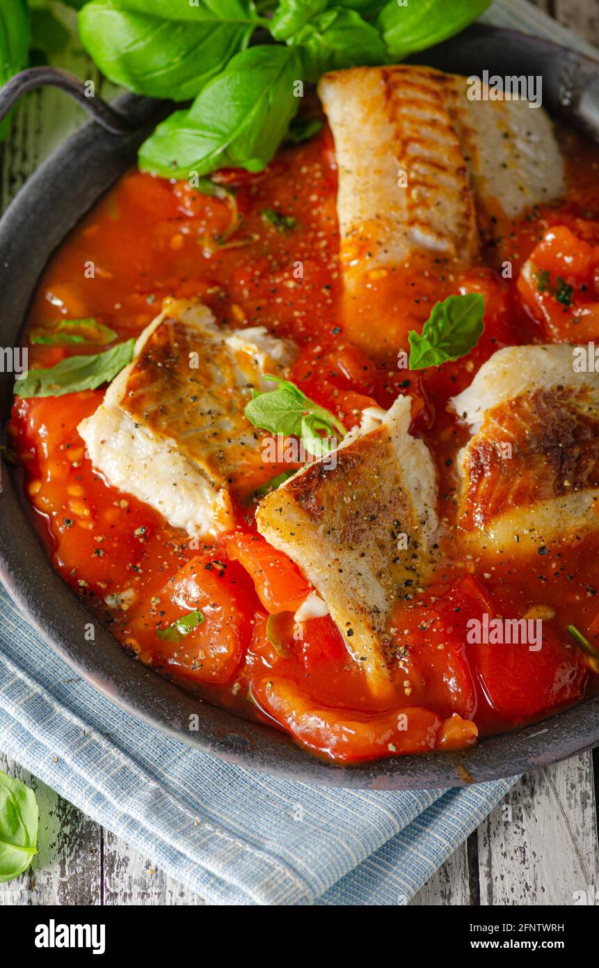 Grilled fish in tomato sauce with basil and herbs Stock Photo - Alamy