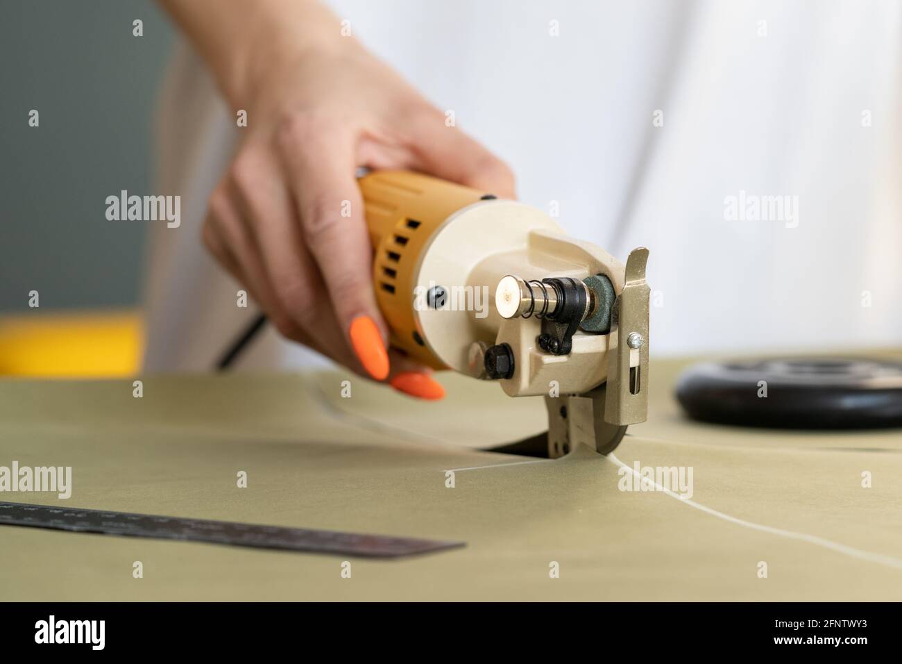 Electric cutter for cutting textile. Closeup of female hand work with ...