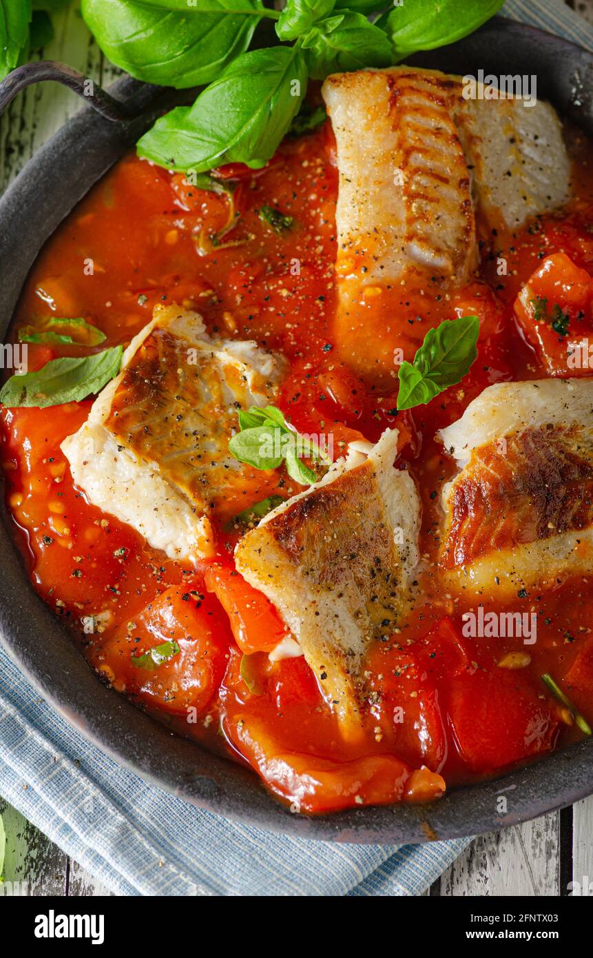 Grilled fish in tomato sauce with basil and herbs Stock Photo - Alamy