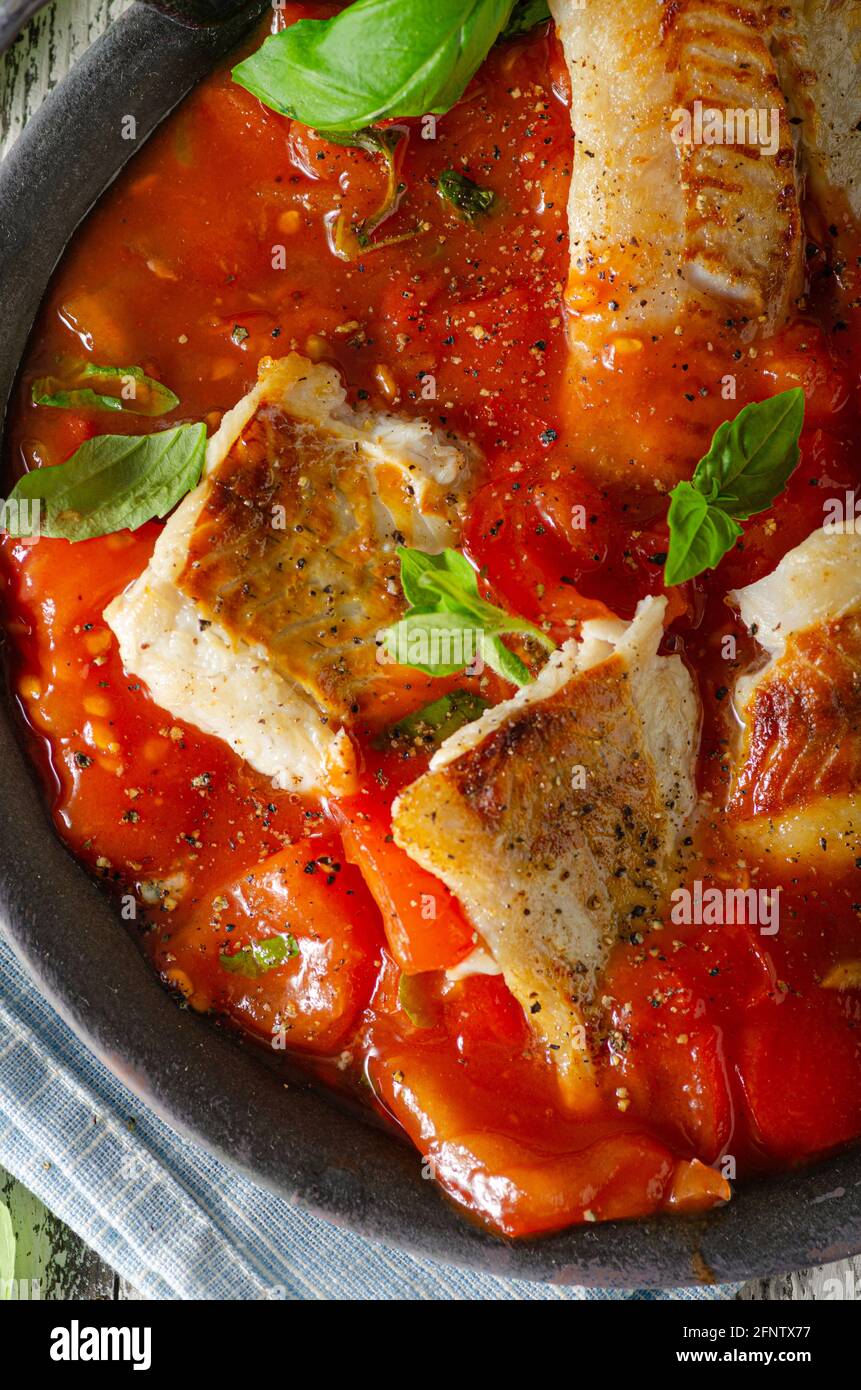 Grilled fish in tomato sauce with basil and herbs Stock Photo - Alamy