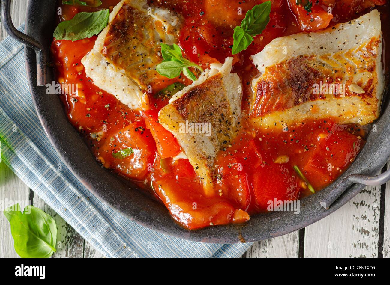 Grilled fish in tomato sauce with basil and herbs Stock Photo - Alamy