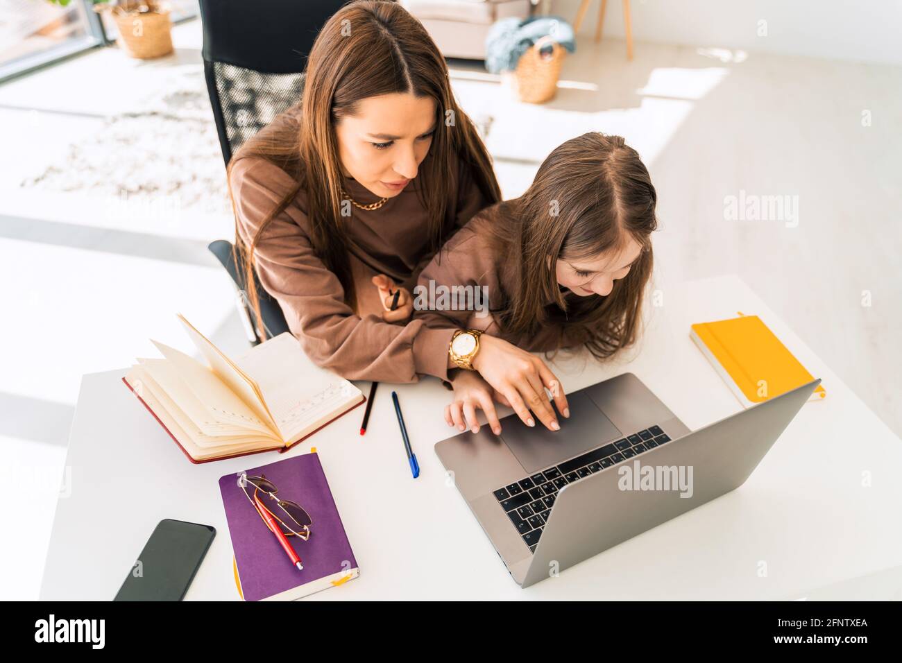 Mom and little daughter doing homework on laptop. Mother teaches the ...