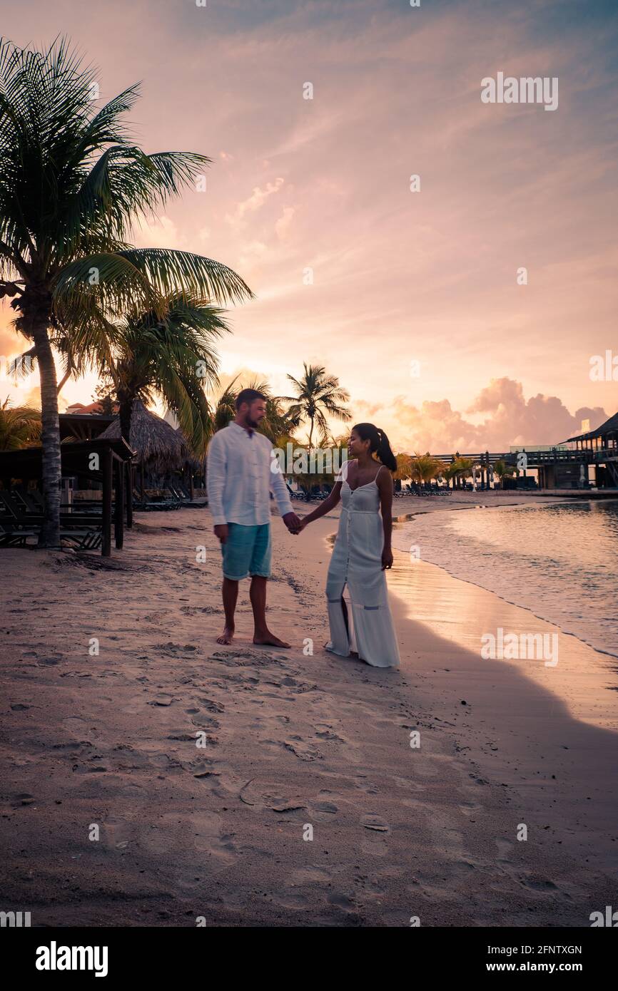 Couple on the beach of Curacao during sunset, men and woman watching ...