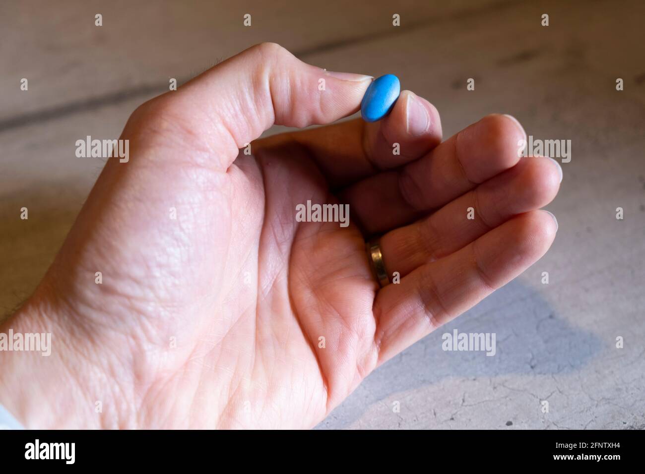 Male hand holding a blue pill Stock Photo - Alamy