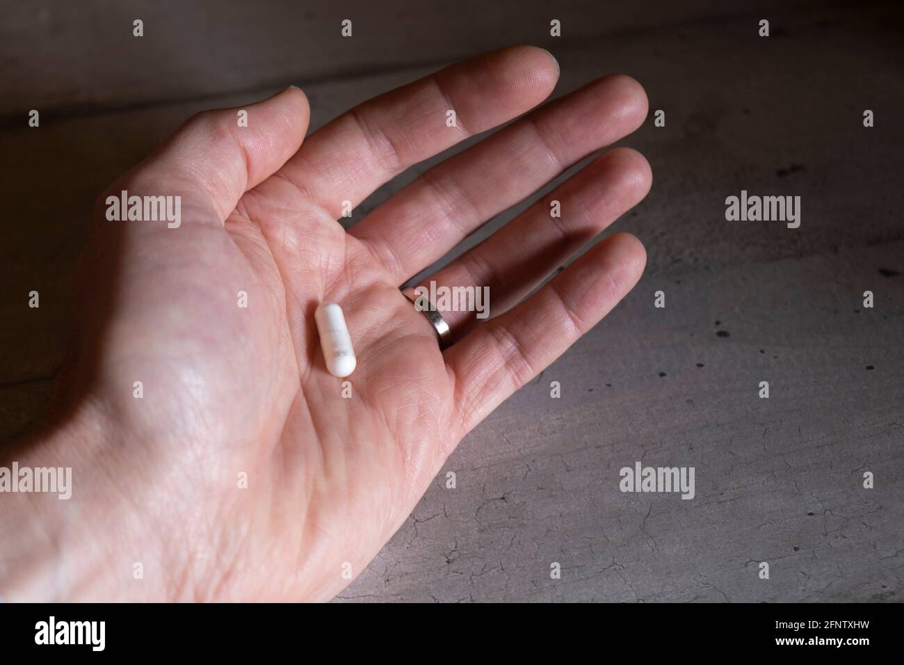 Male hand holding a blue pill Stock Photo - Alamy