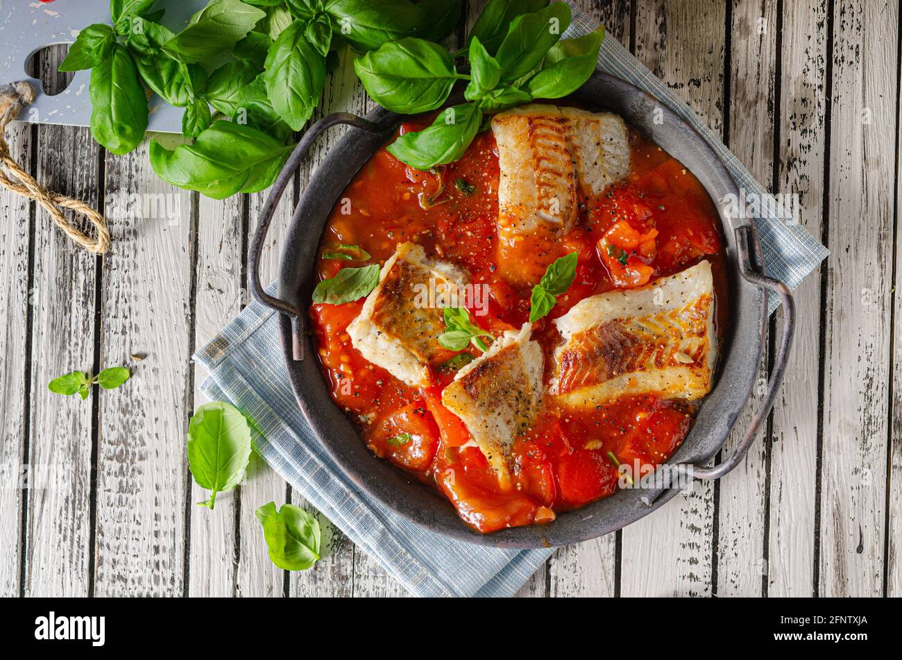 Grilled fish in tomato sauce with basil and herbs Stock Photo - Alamy