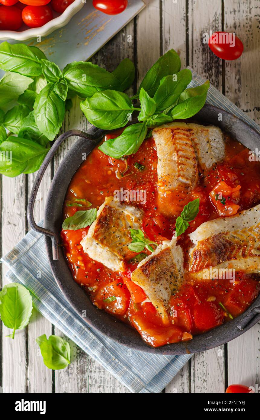 Grilled fish in tomato sauce with basil and herbs Stock Photo - Alamy