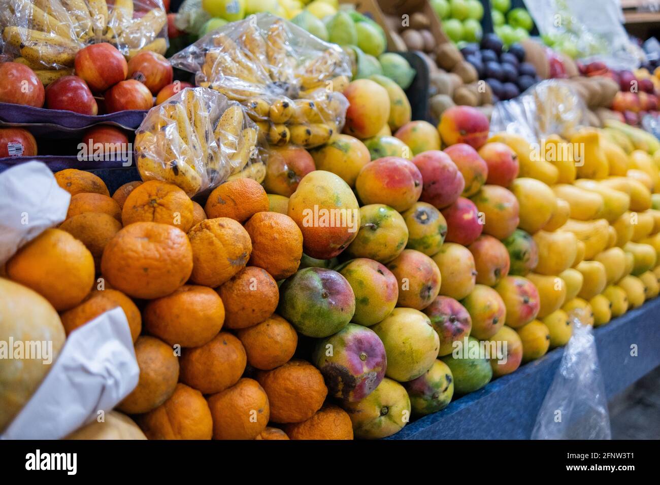 Colorful fruit stand with tangerines, apples, mangoes, bananas, and ...