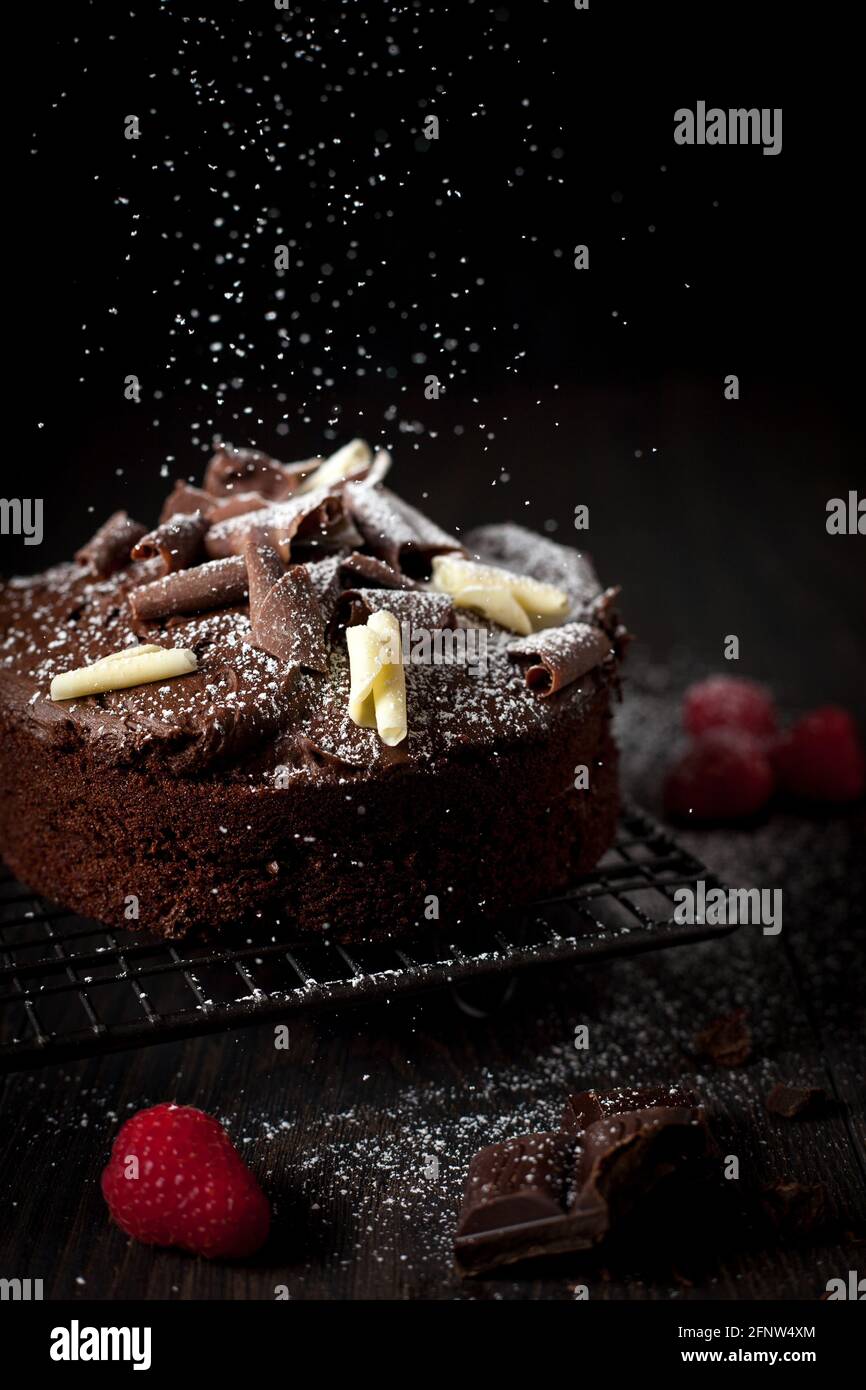 Icing sugar falling onto chocolate gateau Stock Photo - Alamy