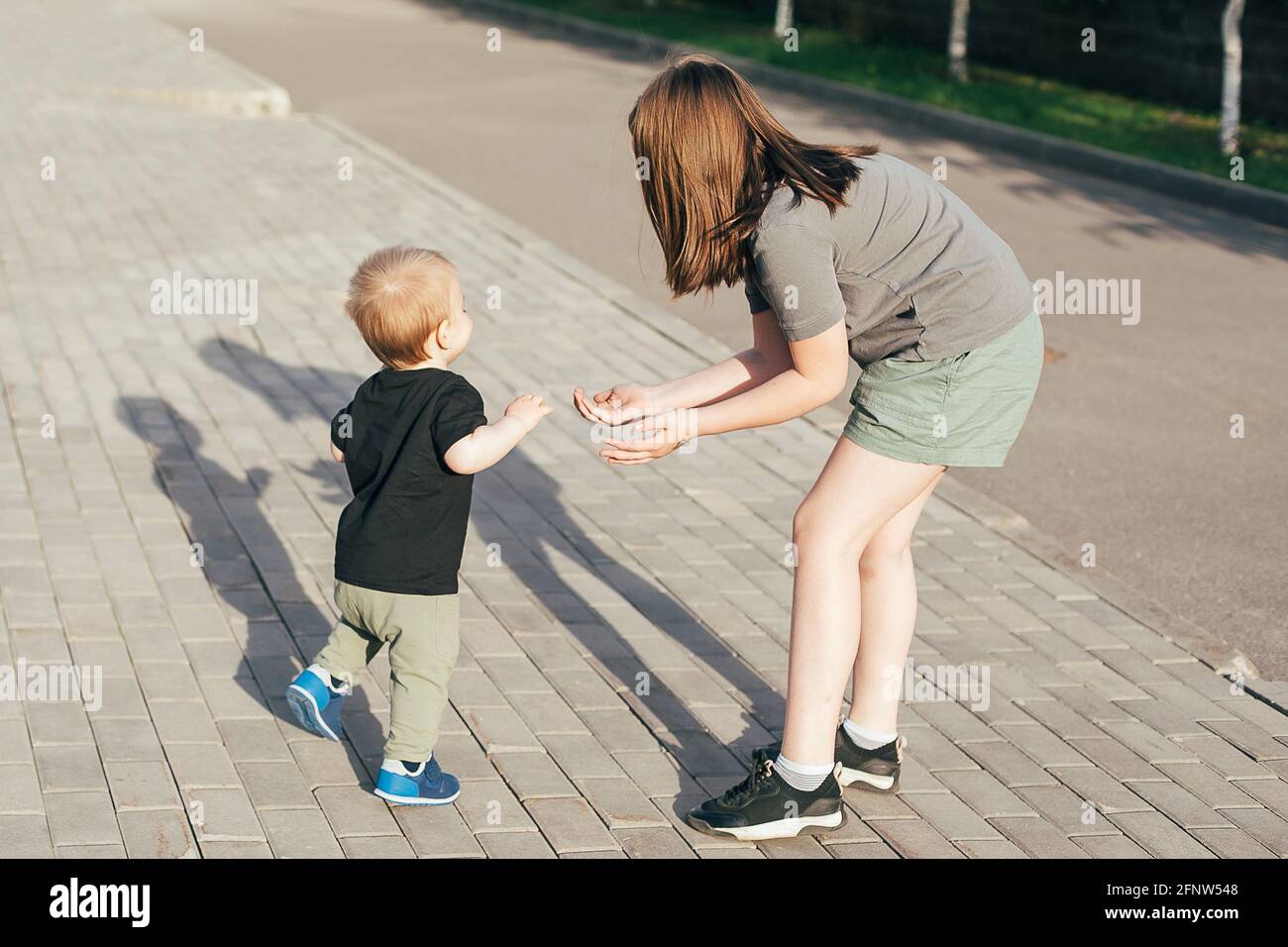 Girl with younger brother walking together. Baby taking first steps ...