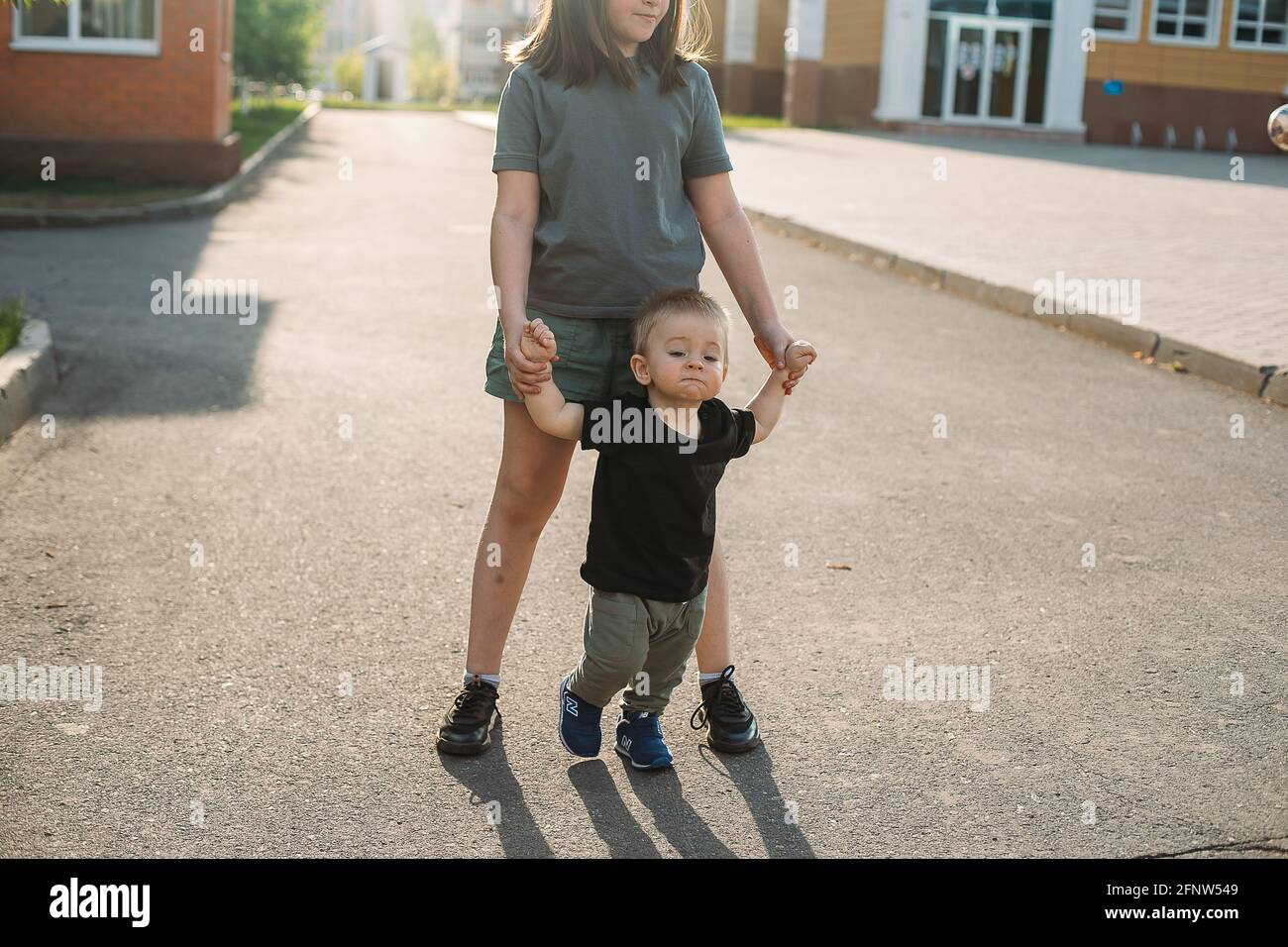 Girl with younger brother walking together. Baby taking first steps ...