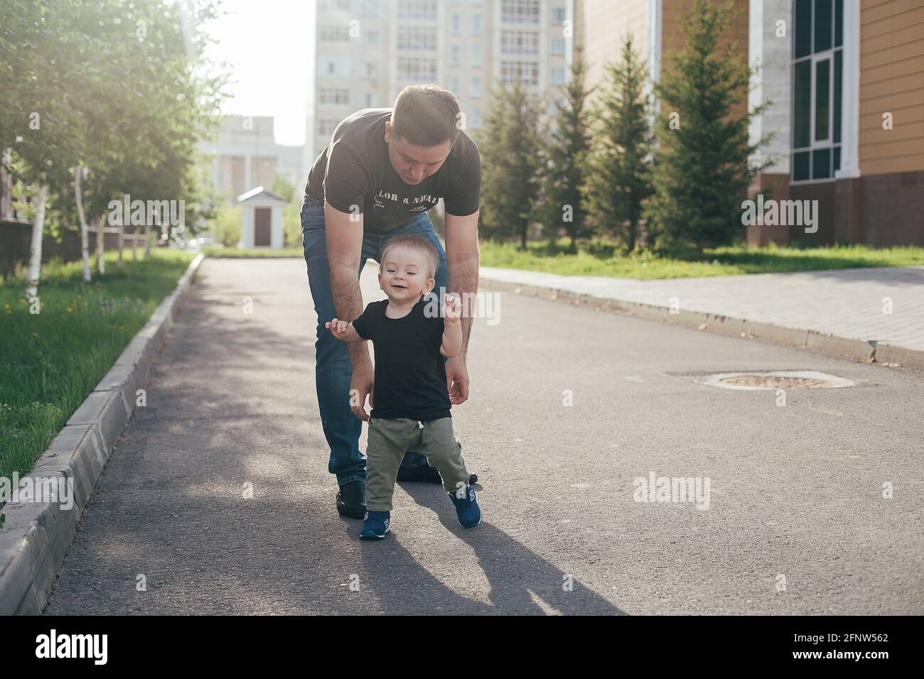 Father and Son walking together. Baby taking first steps with father ...