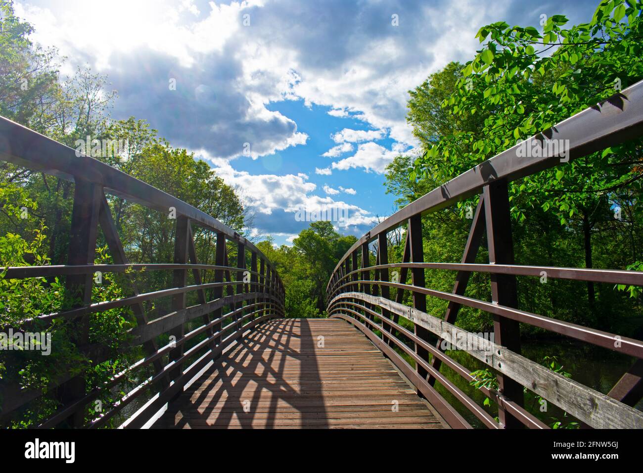 Steel pedestrian footbridge with wooden walkway crossing a narrow ...
