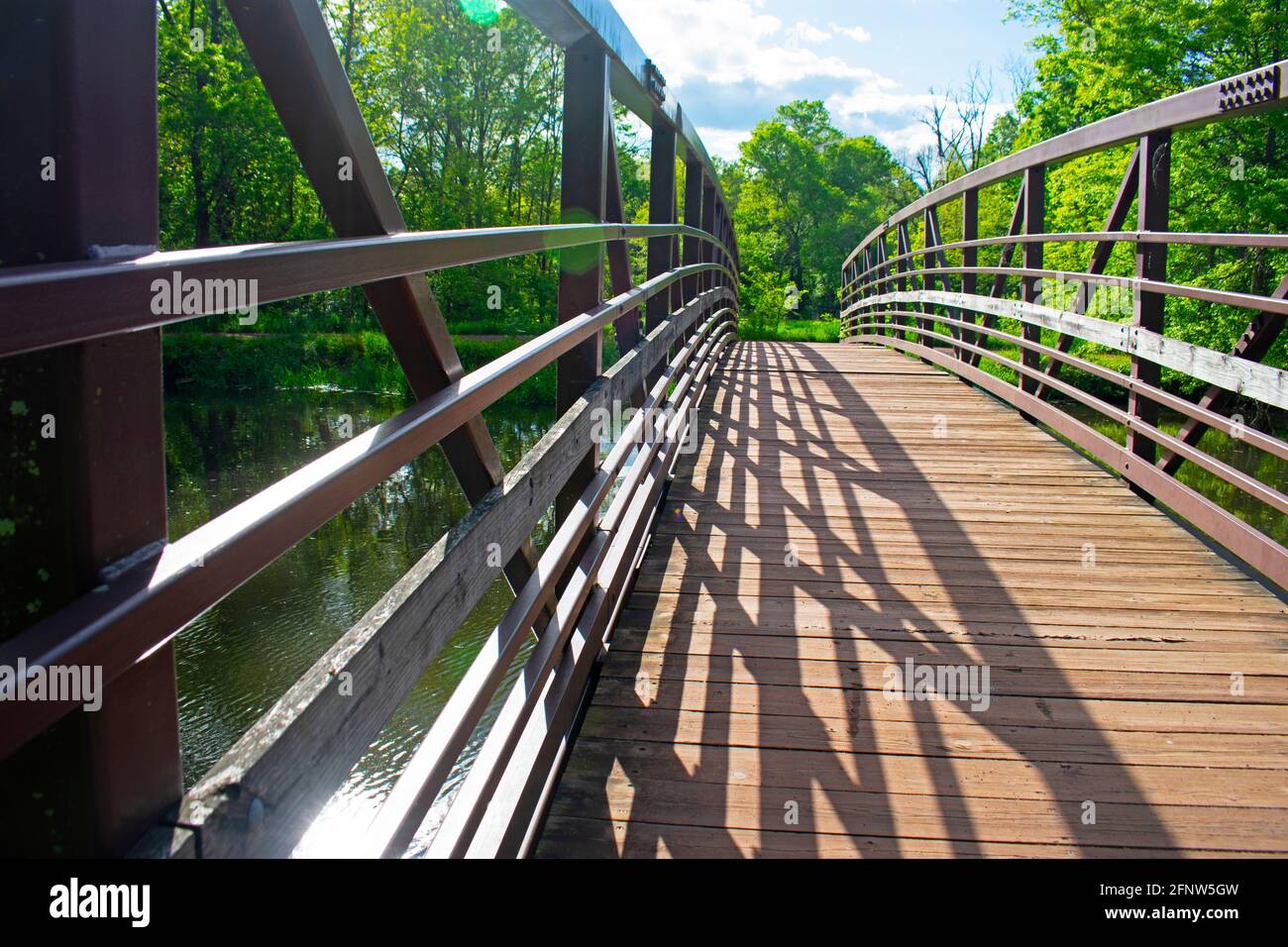 Steel pedestrian footbridge with wooden walkway crossing a narrow ...