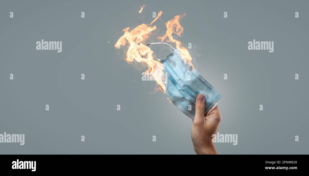 Hand holding a burning medical face mask Stock Photo - Alamy