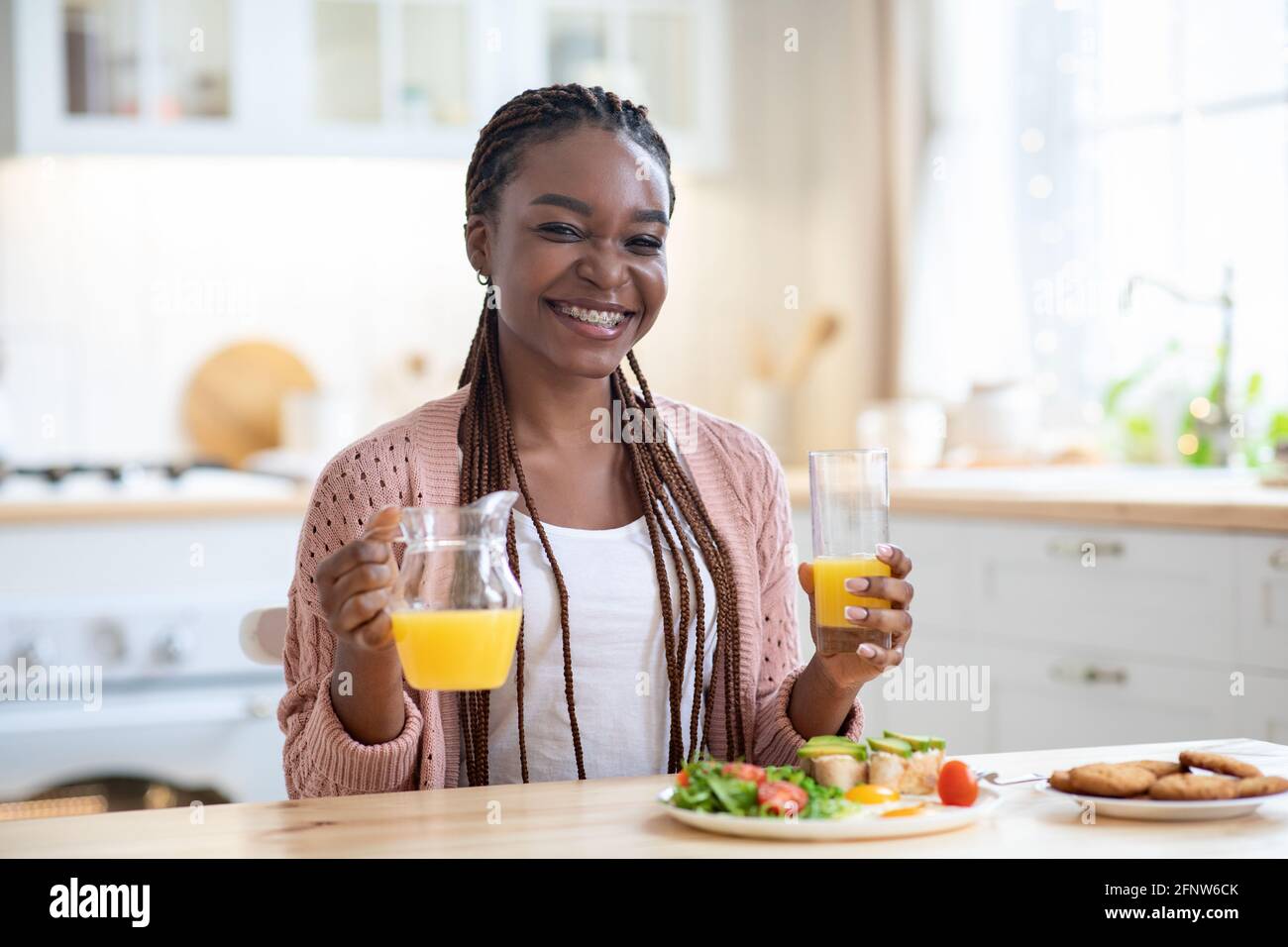 Breakfast At Home. Young happy black lady having tasty meal in kitchen ...