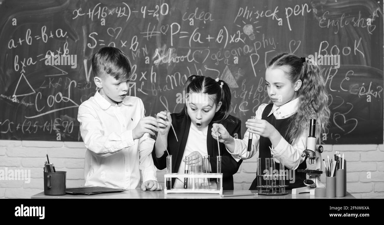 Girls and boy providing experiment with liquids. Test tubes with ...