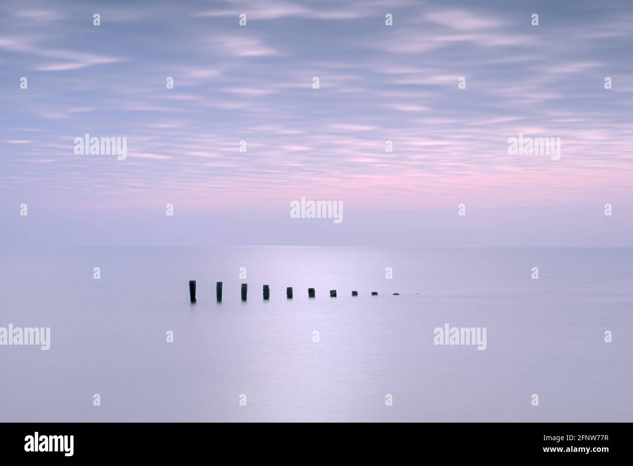 Diminishing posts in a calm sea with pink pastel coloured sky Stock ...