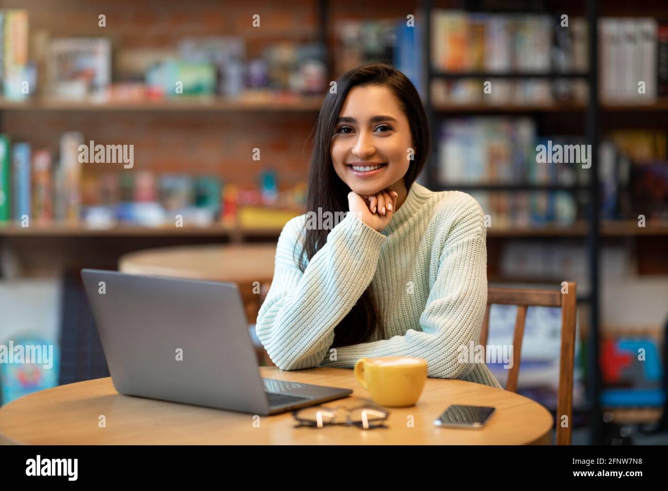 Pretty arab lady using laptop computer at cafe, working distantly and ...