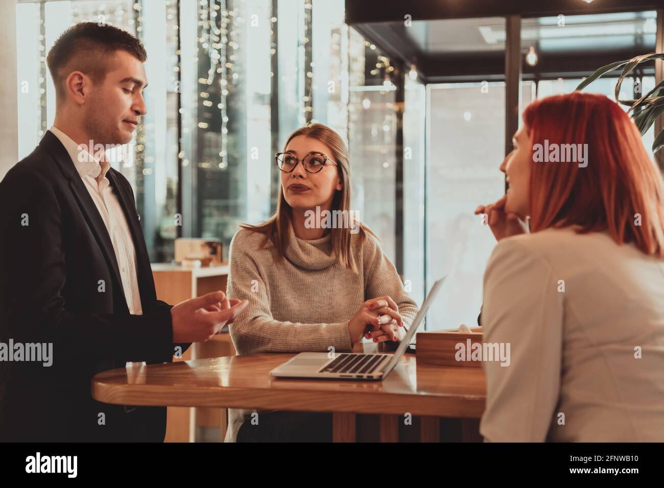 A group of friends hanging out in a cafe, and talking about business ...
