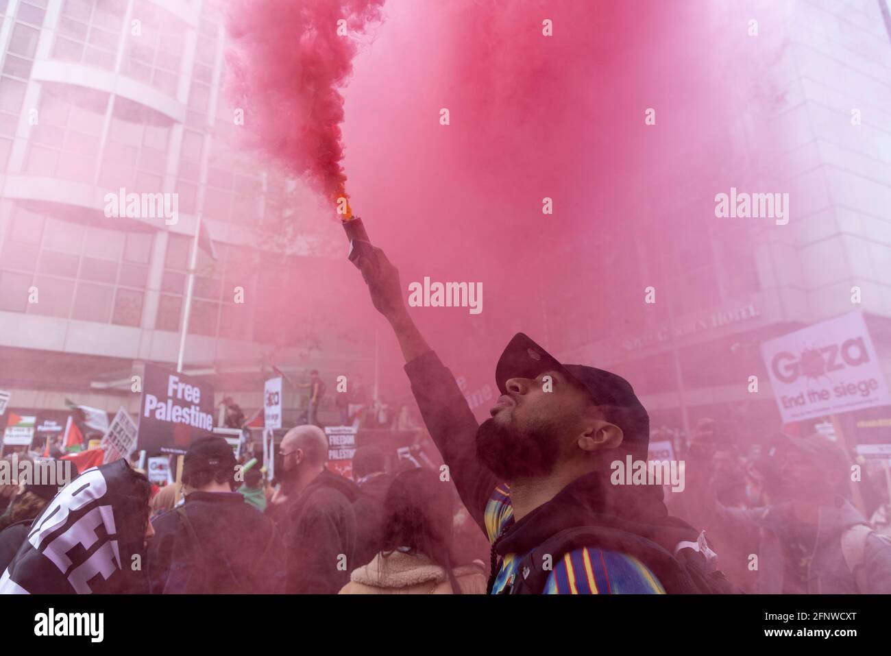 A protester holding a pink smoke bomb above crowd, 'Free Palestine ...