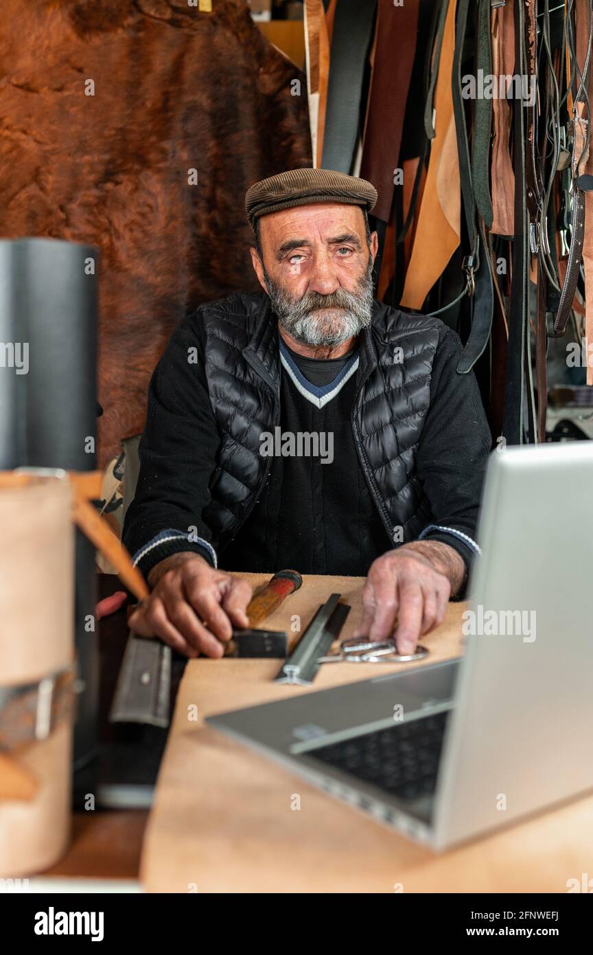 Senior man working with leather in his workplace and looking at the ...