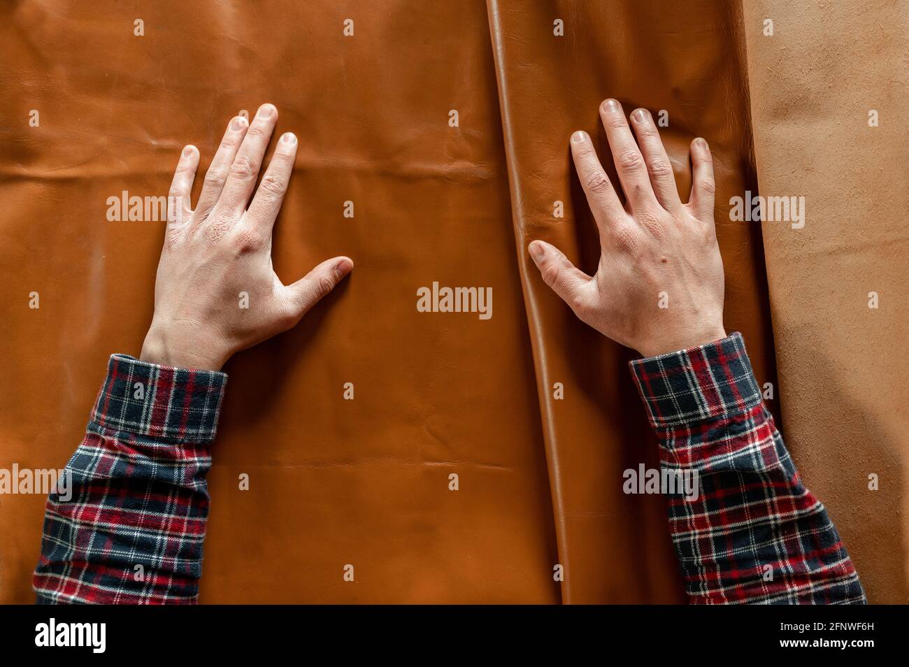 Top view unrecognizable male hands touching a piece of genuine leather ...