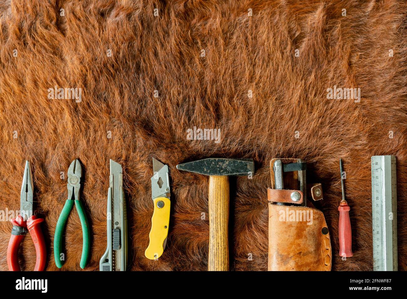 Top view work tools in a row for leather and craftsmanship on hairy cow ...