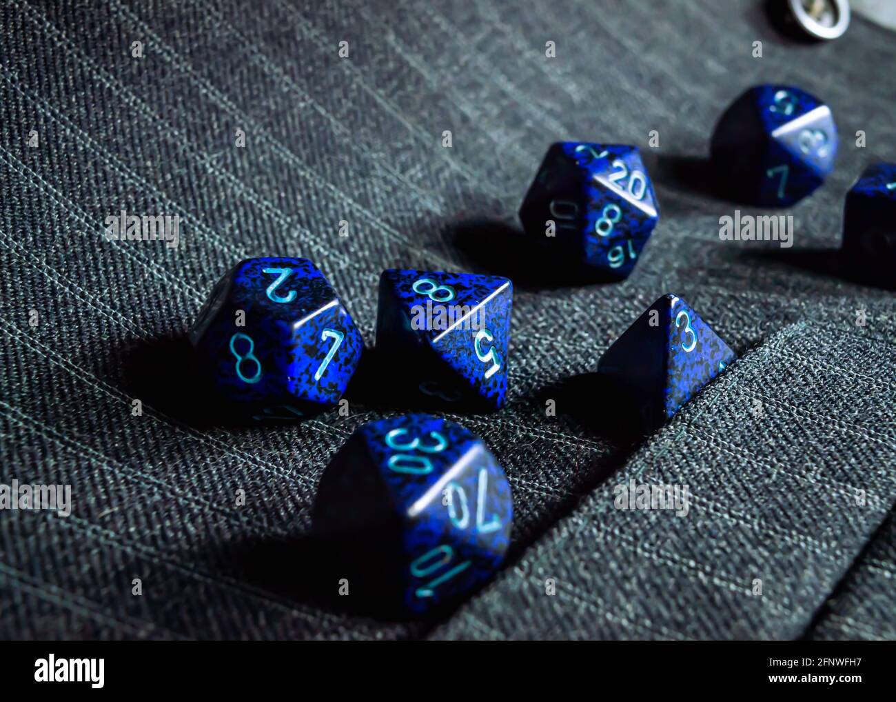 Close-up of a set of blue role-playing game dice on a pinstriped grey ...