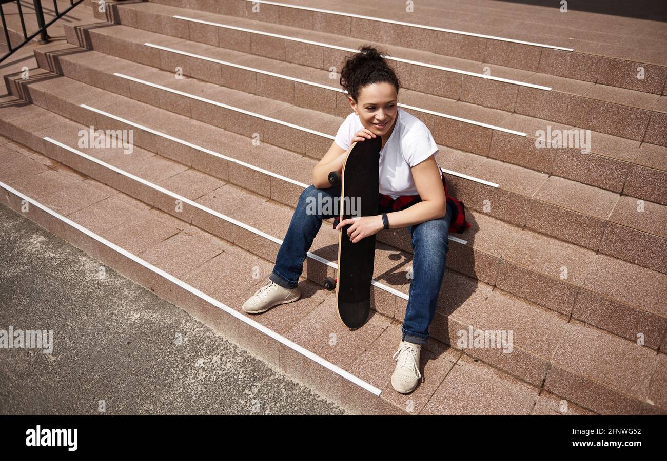 High angle view of a happy smiling mixed race woman with skateboard ...