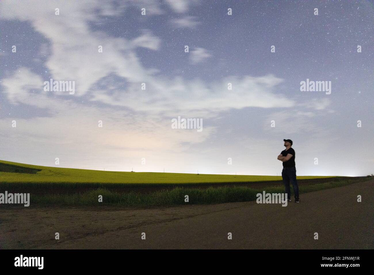 Man starring at the cloudy night sky with light pollution in the ...