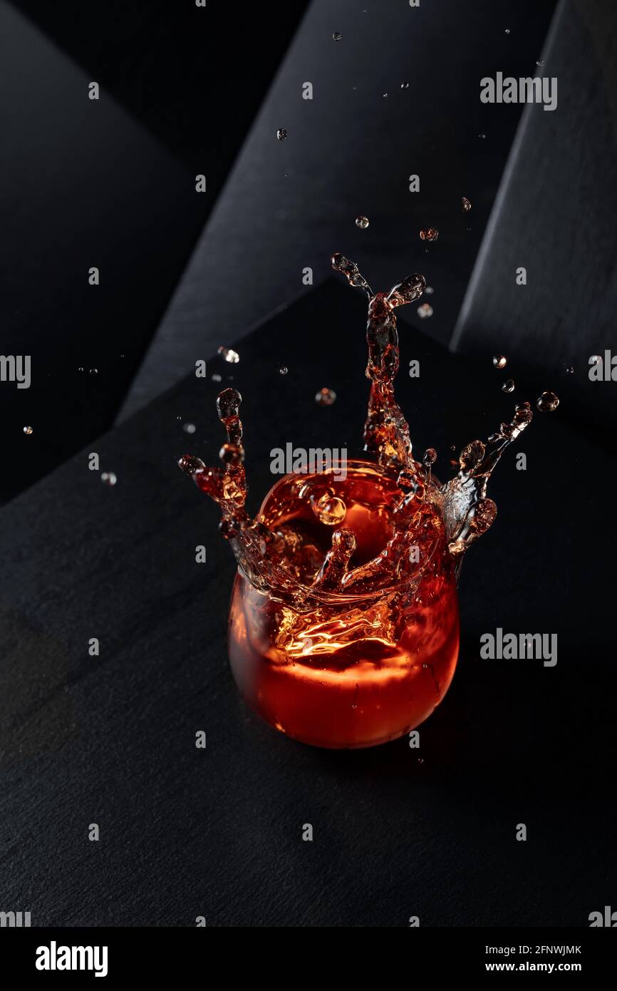Ice cubes fall into a glass of whiskey creating splashes Stock Photo - Alamy