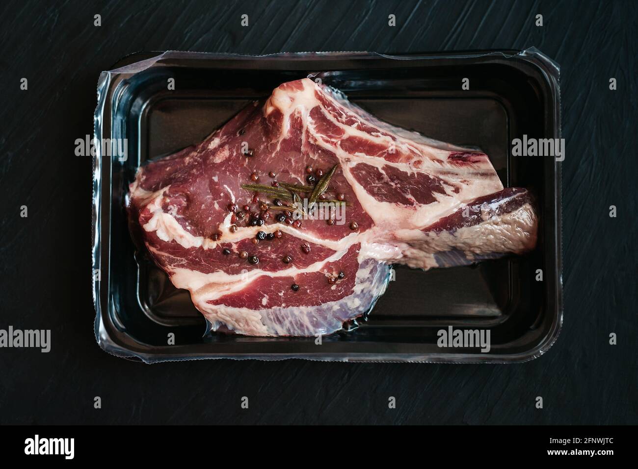 Raw beef steak and spices vacuum Packed on dark background. Top view ...