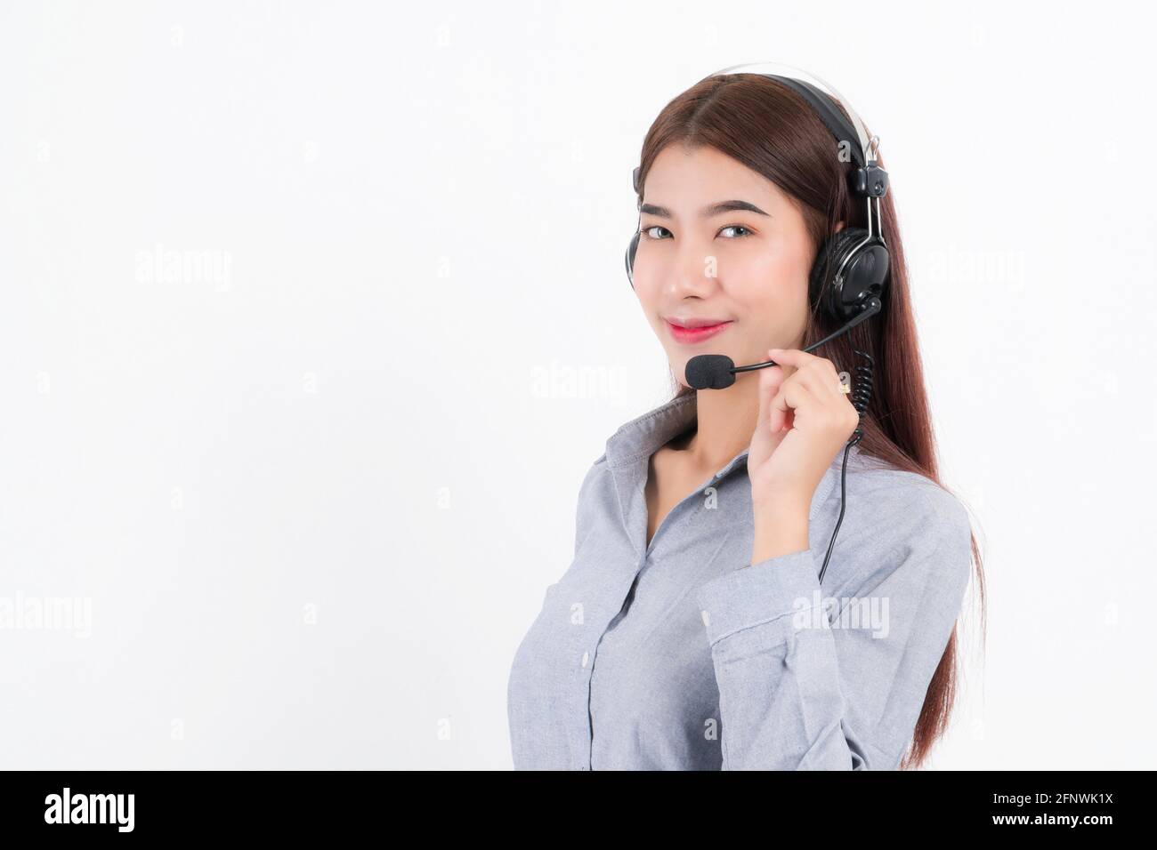 Portrait of happy smiling female customer support phone operator short hair, wearing a white ...