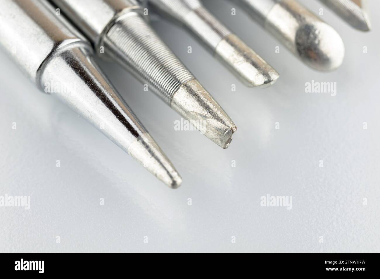 Close up of soldering tips on glass table, silver background with ...