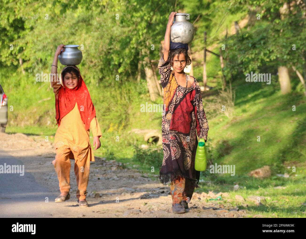 Kashmiri children carrying water pots on their heads as they are ...