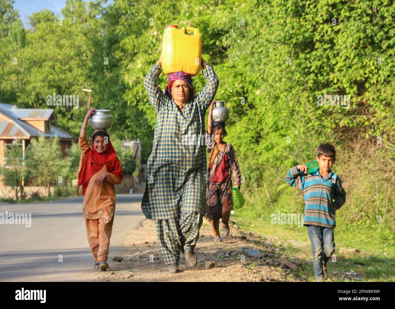 Kashmiri women with her children carrying water pots on their heads as ...