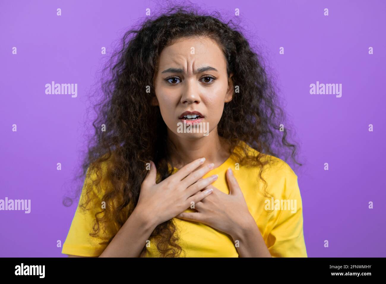 Unpleasantly surprised and shocked girl on violet studio background ...